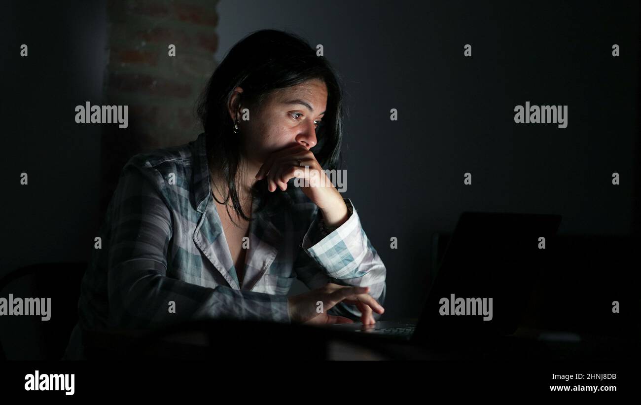 Woman face reading content online in front of computer screen at night ...