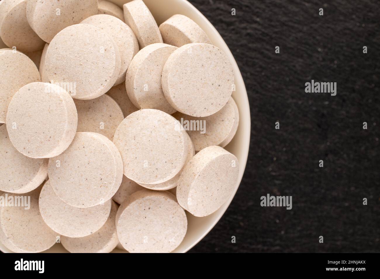 Several medical tablets with a ceramic white saucer on a slate stone ...