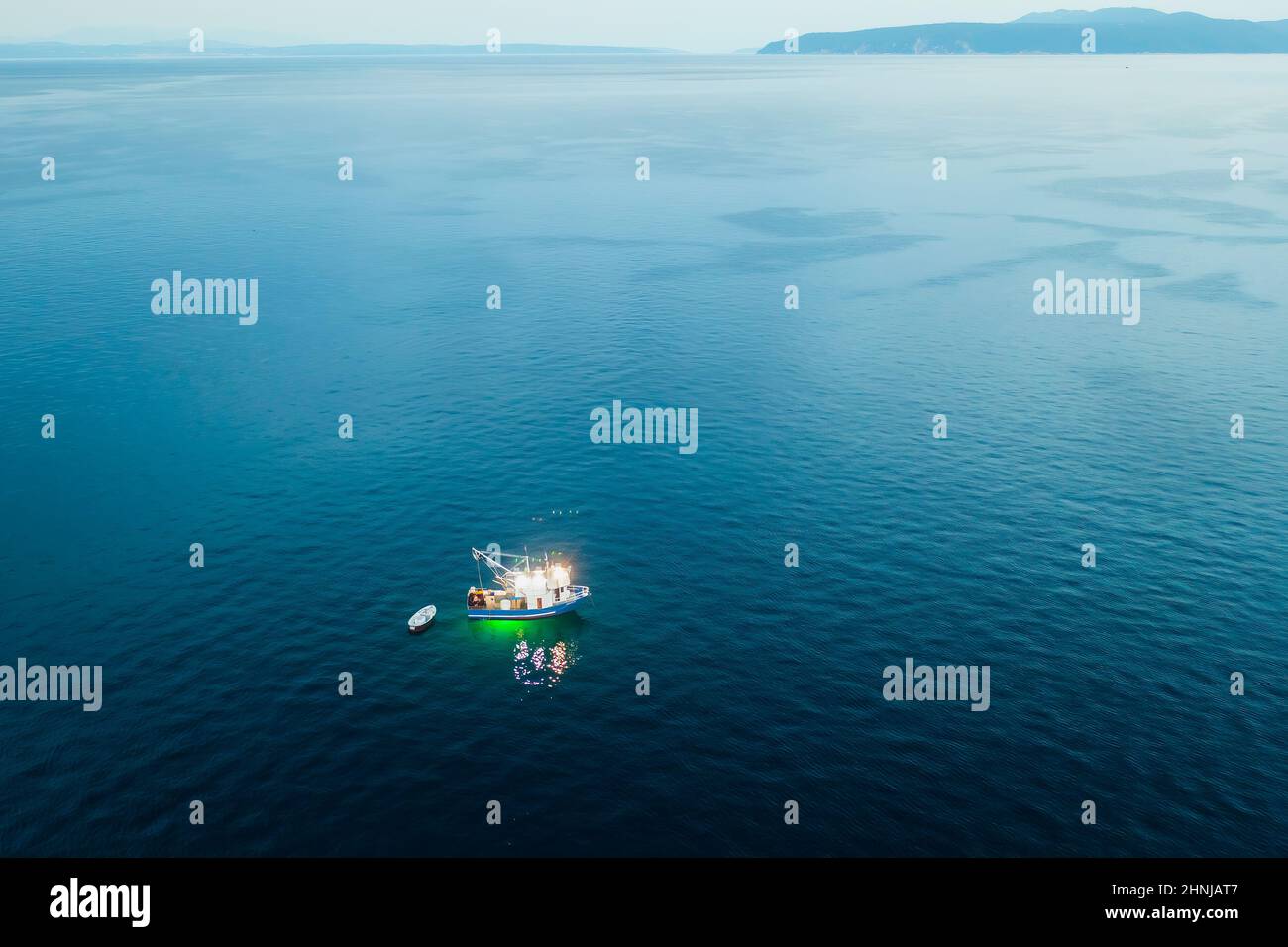 Evening fishing in Adriatic sea with boat drifting on calm water ...