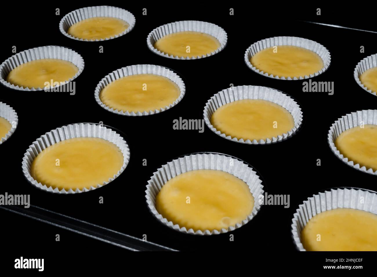 Uncooked homemade cupcakes, muffins in electric oven, black background ...
