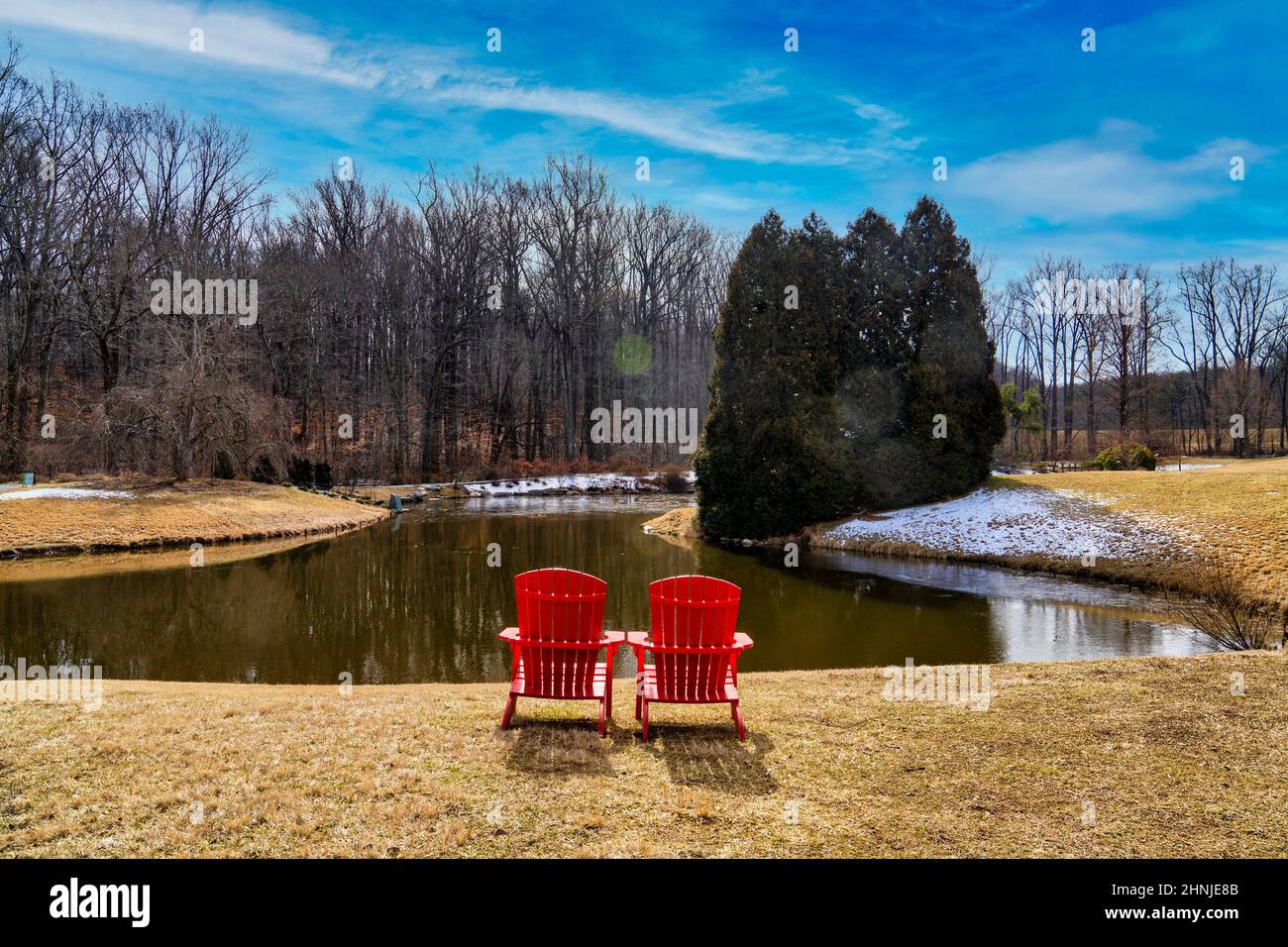 Two red chairs in a meadow by the lake Stock Photo - Alamy