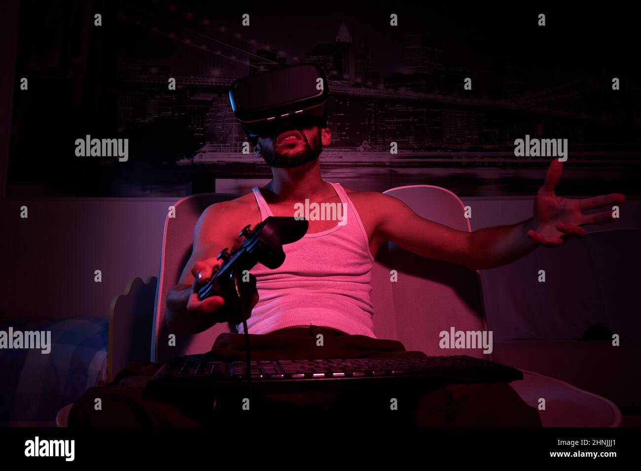 a thirty-year-old gamer in vr glasses with a keyboard and a joystick in ...