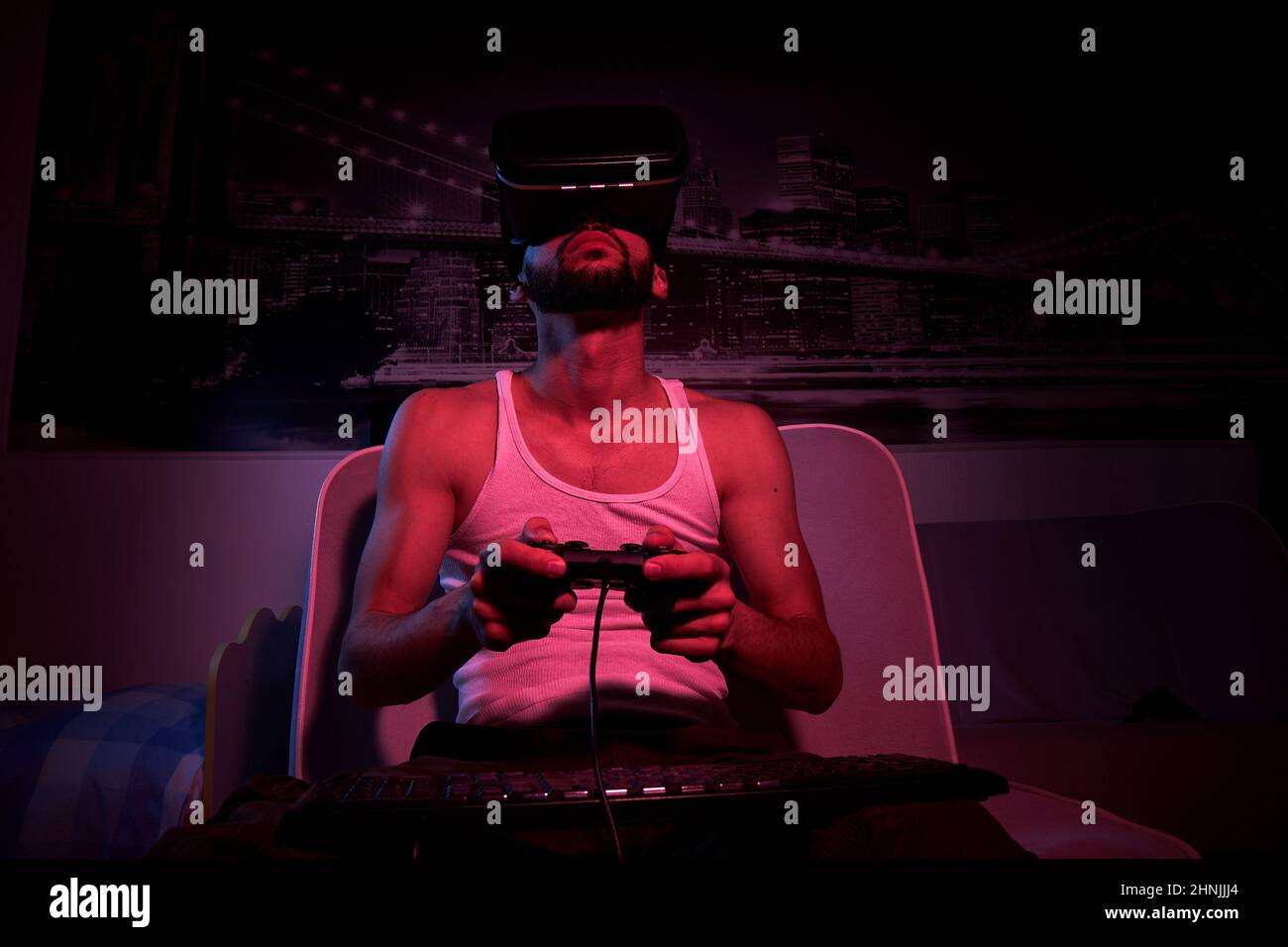 a thirty-year-old gamer in vr glasses with a keyboard and a joystick in ...