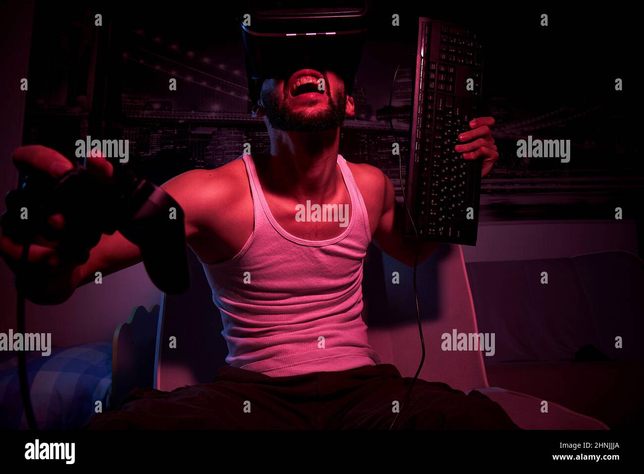 a thirty-year-old gamer in vr glasses with a keyboard and a joystick in ...