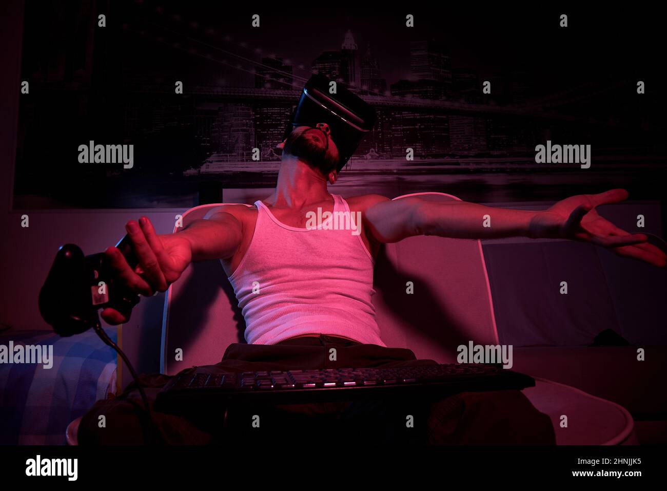 a thirty-year-old gamer in vr glasses with a keyboard and a joystick in ...