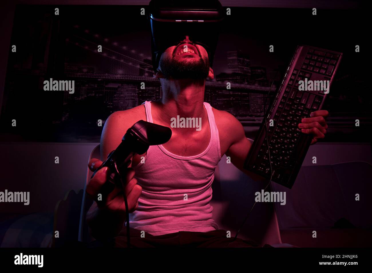 a thirty-year-old gamer in vr glasses with a keyboard and a joystick in ...