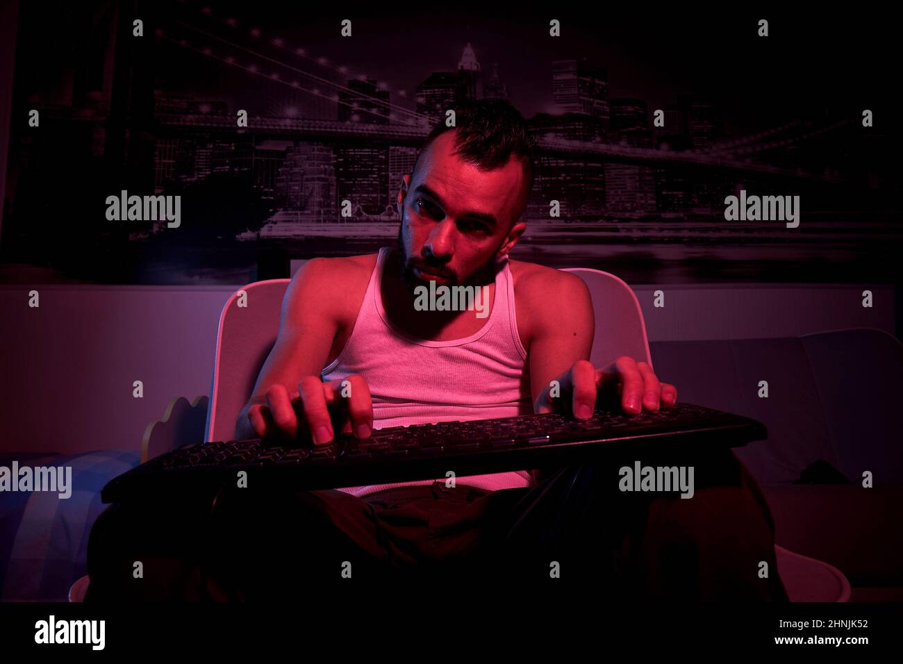 a gamer of thirty years old with a keyboard in his hands plays computer ...