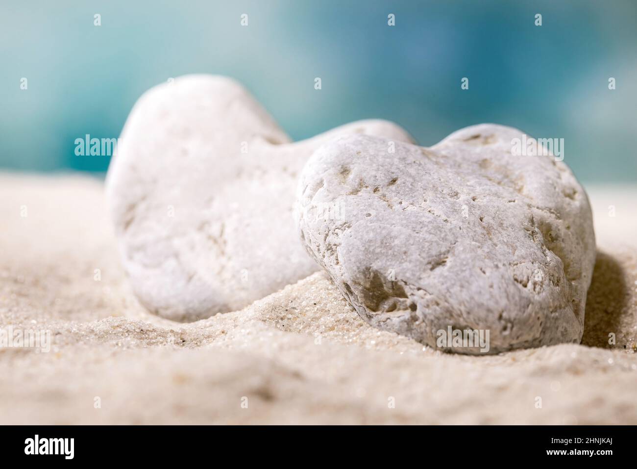 Two heart shape stones laying on summer sand sea beach with waves at ...