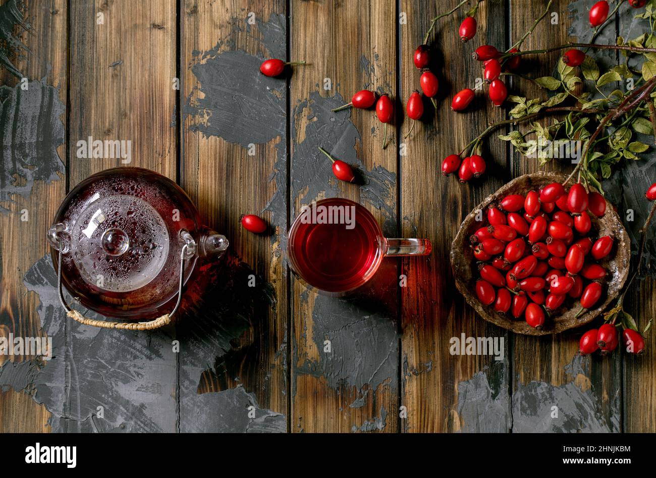 Rose hip berries herbal tea in glass teapot and cup standing on old ...