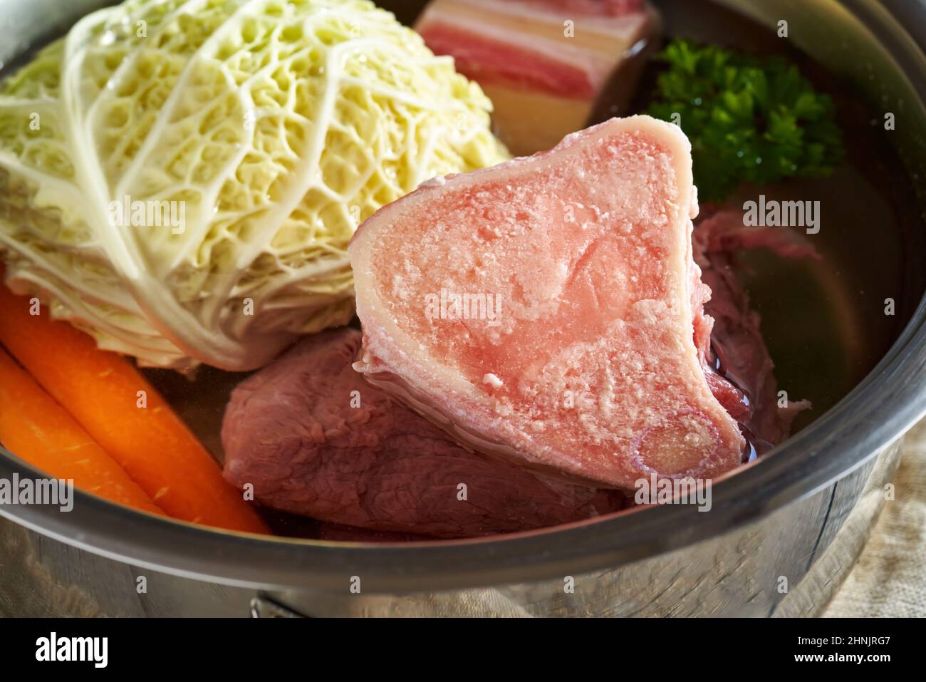 Beef marrow bones, meat and fresh vegetables in a pot of water ...