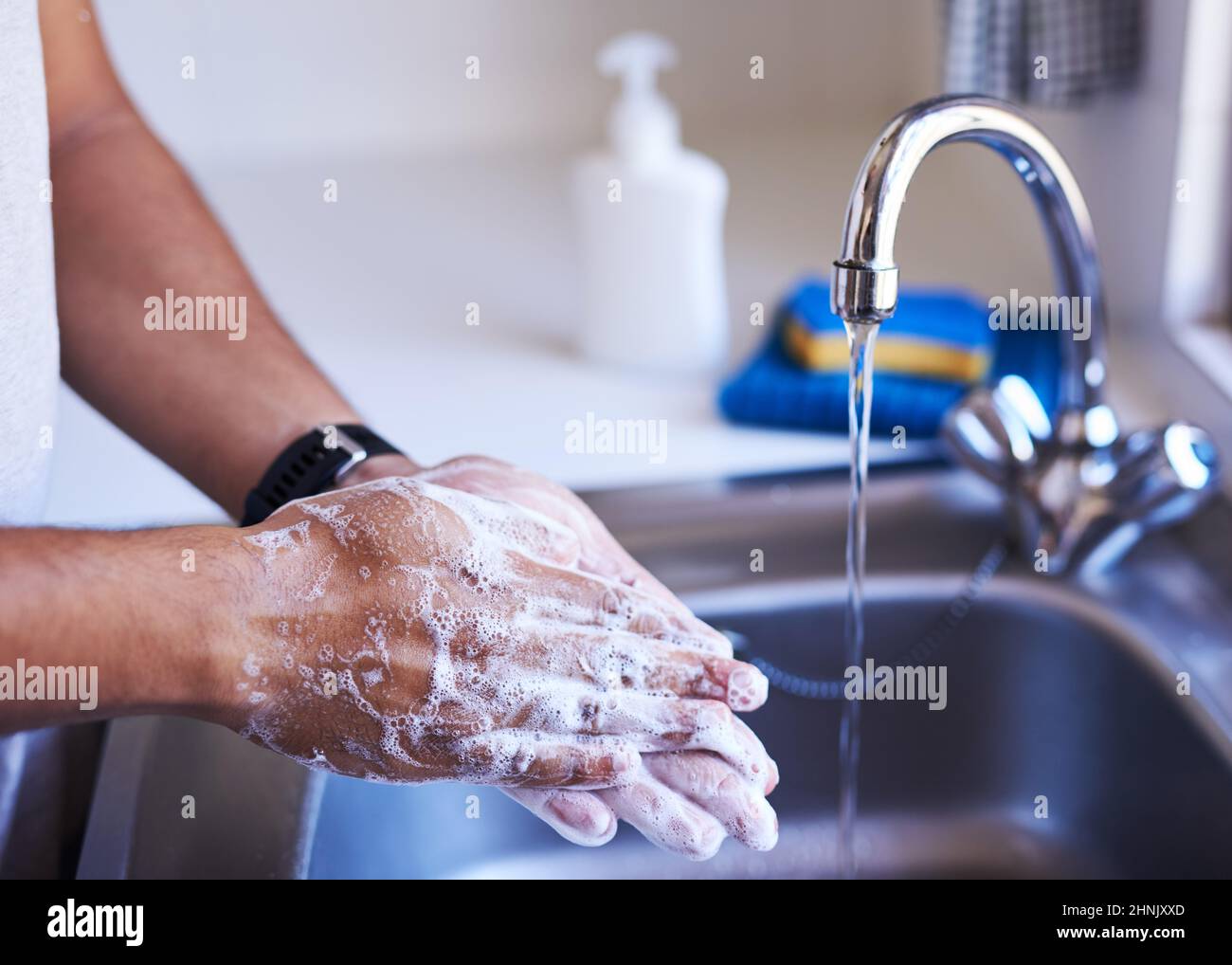 Close up shot of an adult man washing his hands in the kitchen sink ...