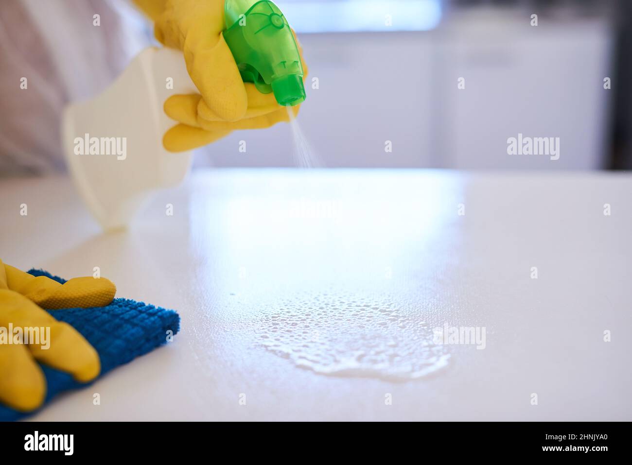 A cleaning professional sprays a kitchen counter with sanitiser Stock ...
