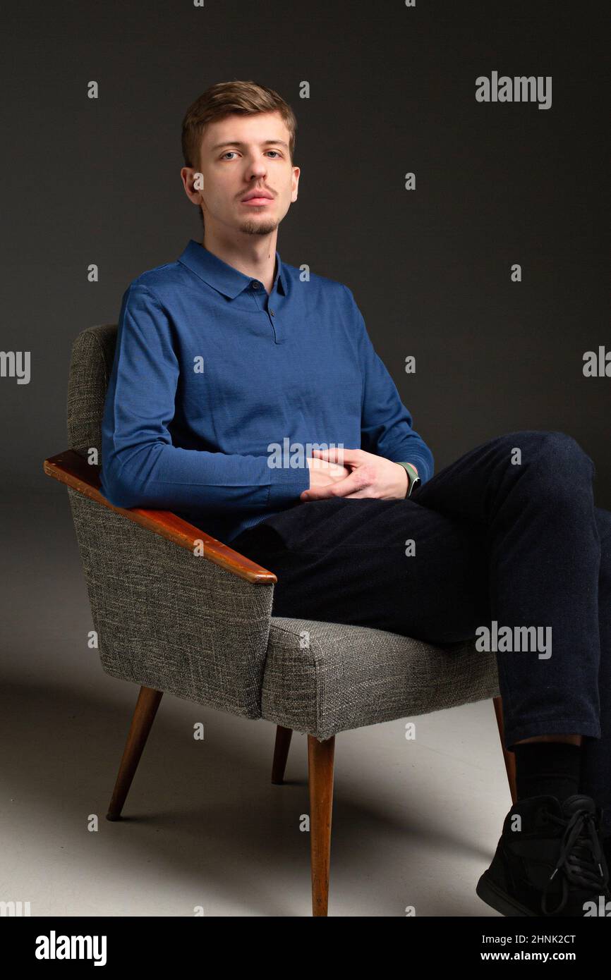 Young blond european man with short beard and mustache sitting isolated ...