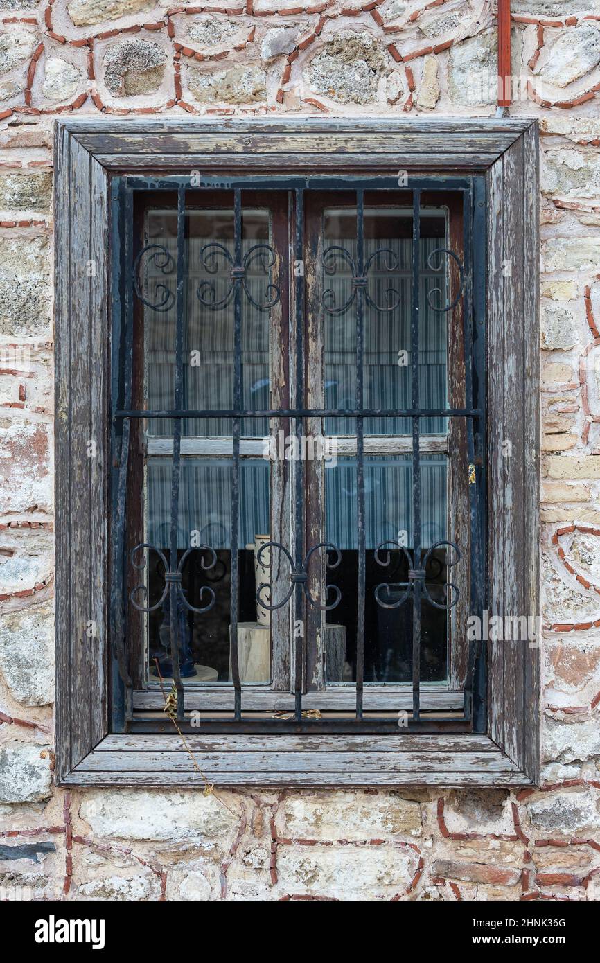 Close-up brown wooden vintage window behind bars in an old stone house ...