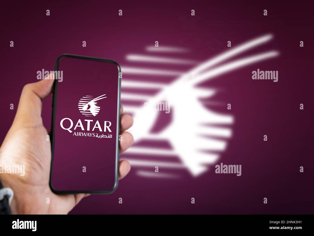 A hand holding a phone with the Qatar Airways airline app on the screen ...