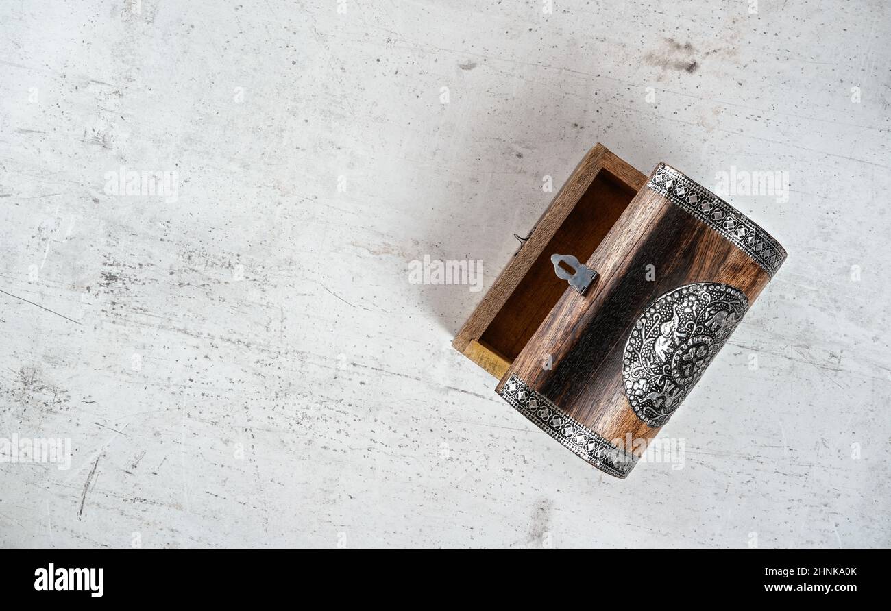 Small wooden decorated empty chest lid opened, on white stone board ...