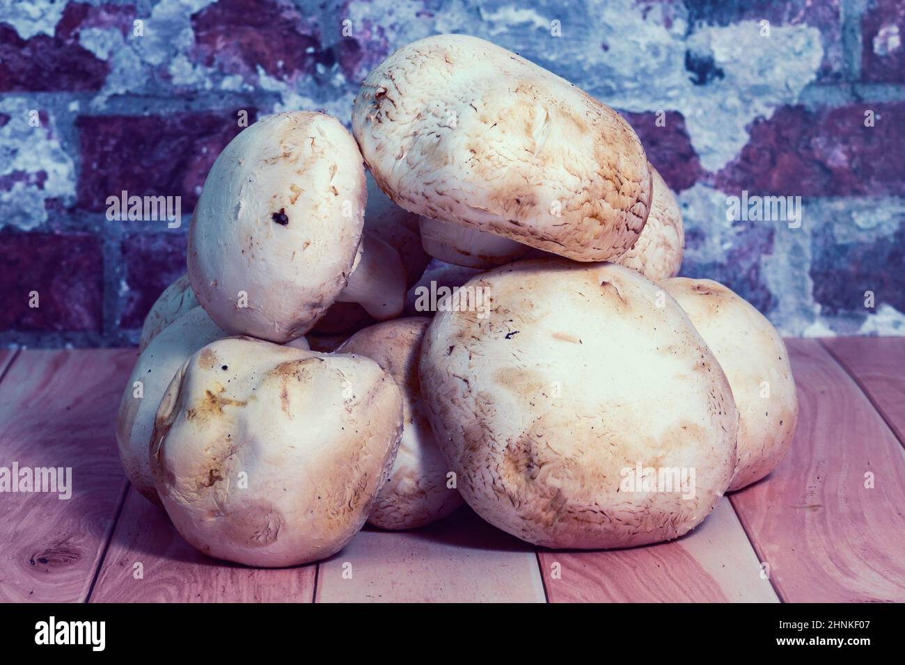 Fresh champignons lie on the table against the background of a brick ...