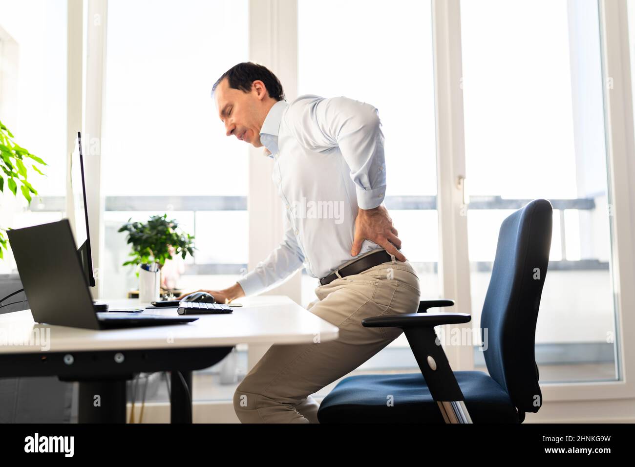 Back Pain Bad Posture Man Sitting In Office Stock Photo - Alamy