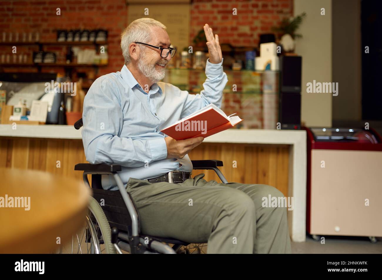 Adult disabled man in wheelchair reading a book, disability, bookshelf ...