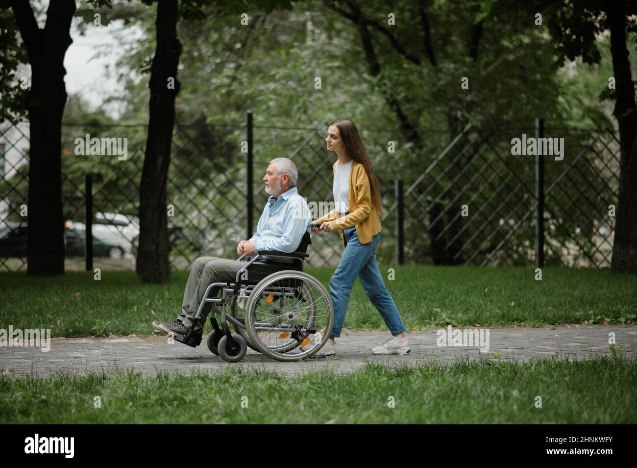 Daughter and disabled father in wheelchair on a walking path, happy ...