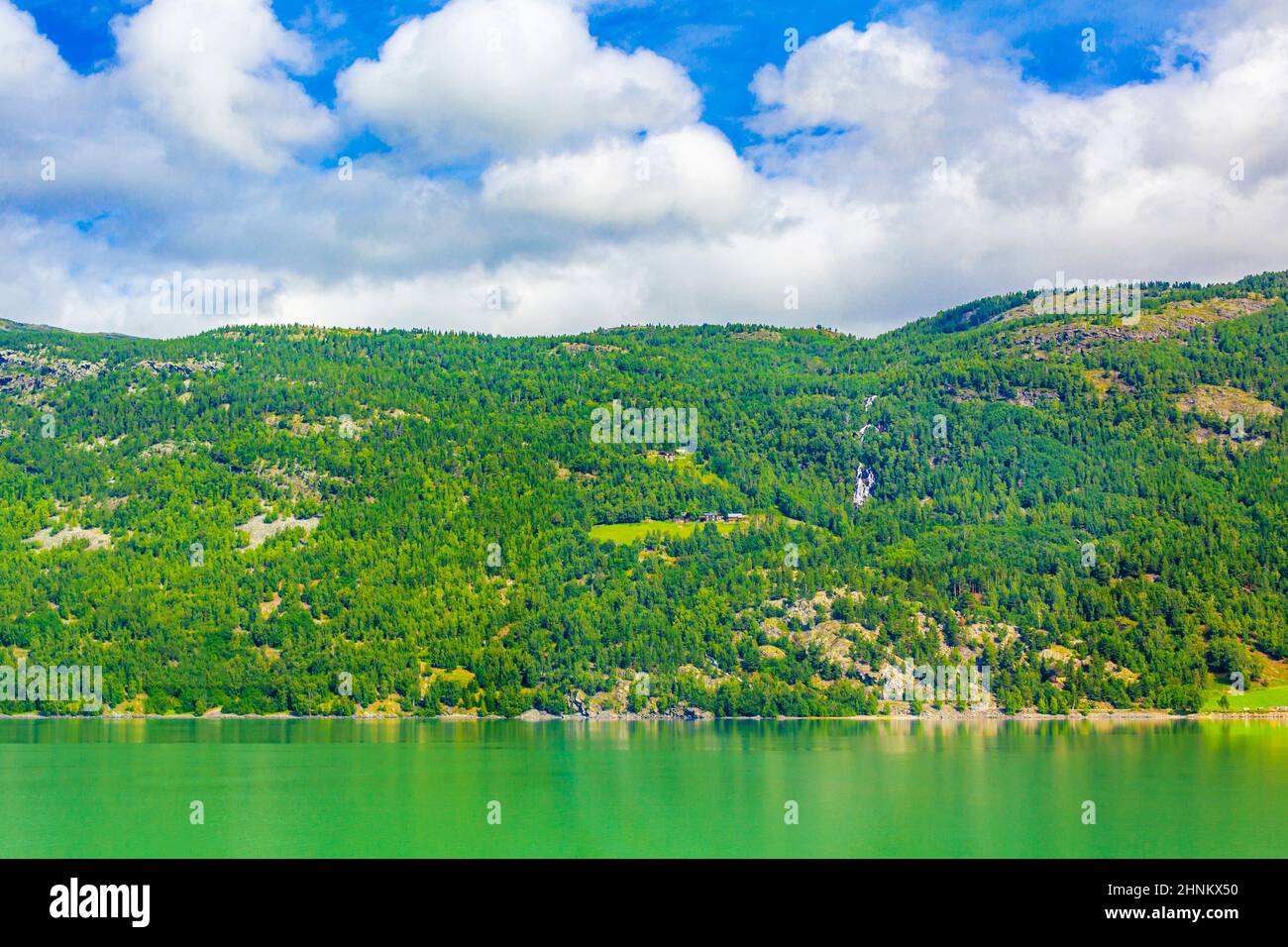 Turquoise green water flows in a fjord river through mountains and ...