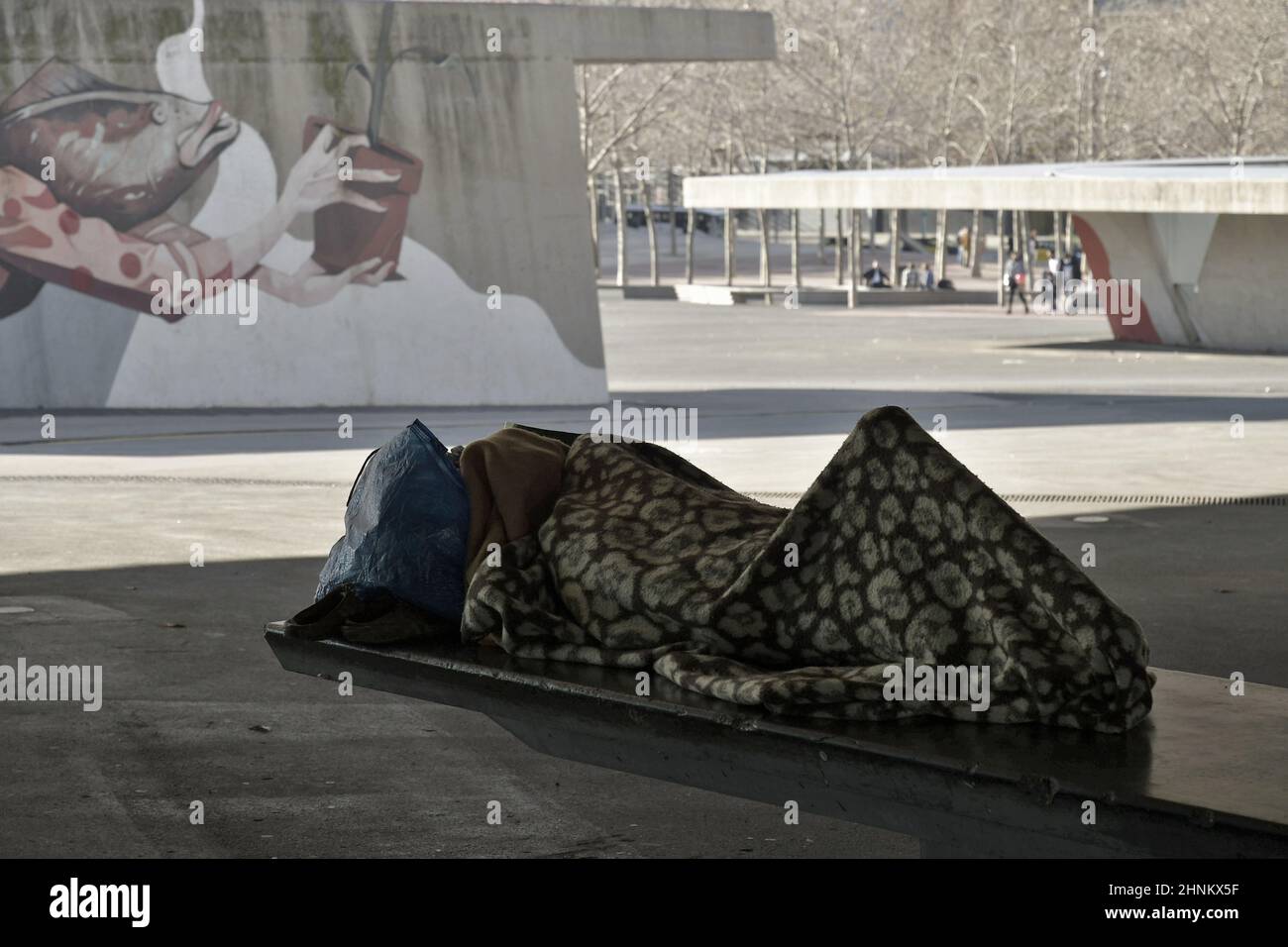 Homeless person covered with blanket sleeping on the bench in Barcelona ...