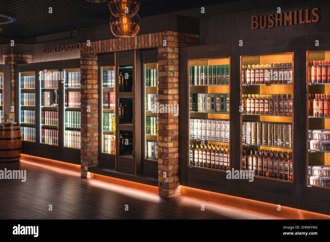 Variety of Bushmills whiskey in a rows on illuminated shelfs on a ...
