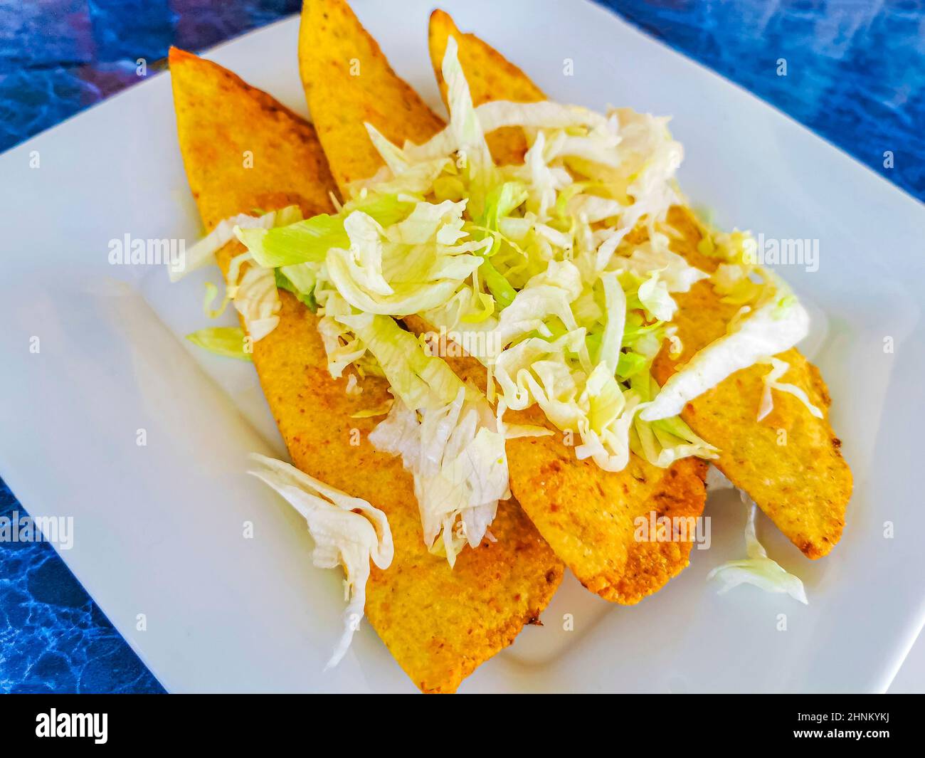 Mexican empanada with cabbage and hot sauce on white plate blue ...