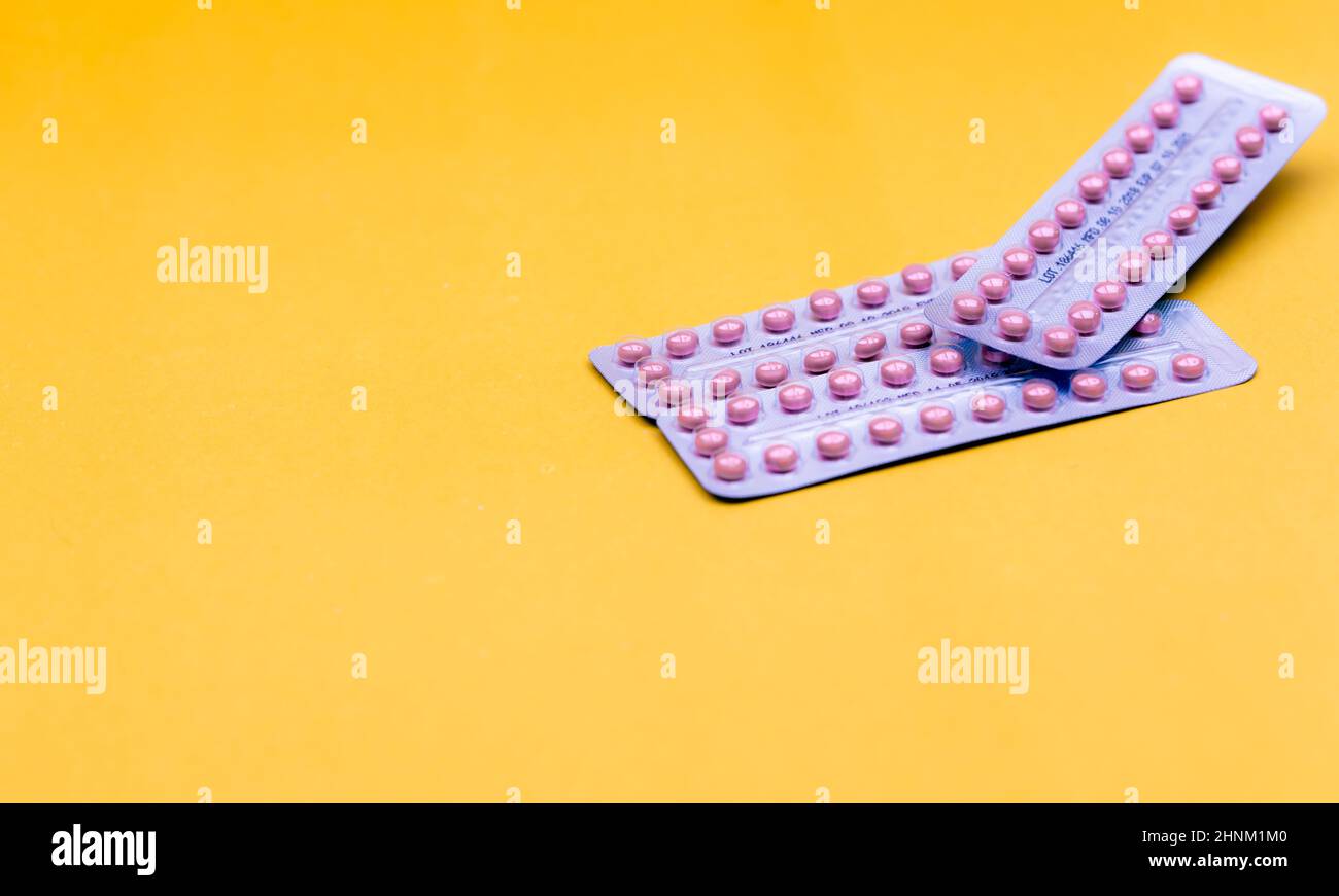 Blister packs of contraceptive pills on yellow background. Hormone ...