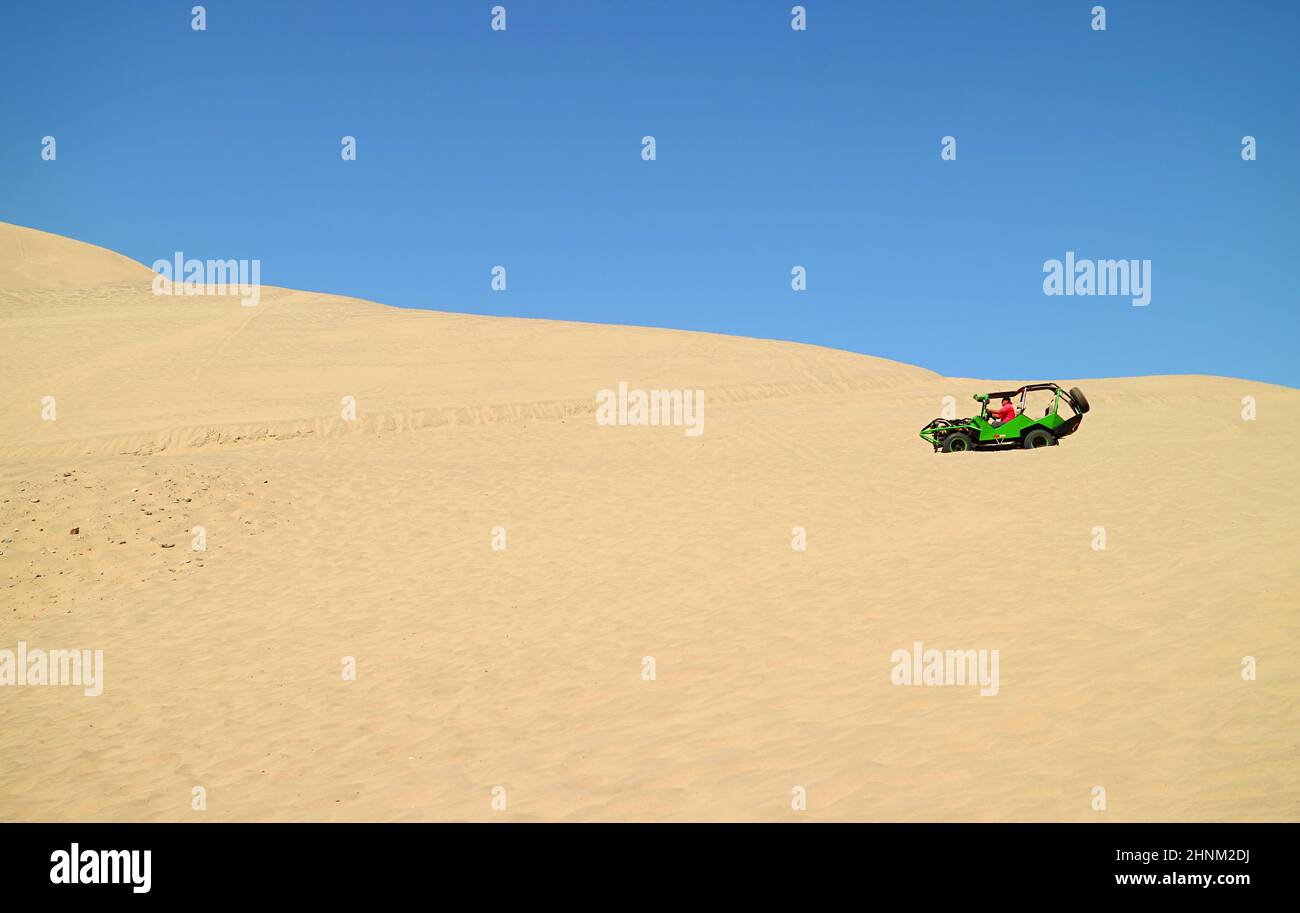 A dune buggy running on the sand dunes of Huacachina desert, Ica region ...