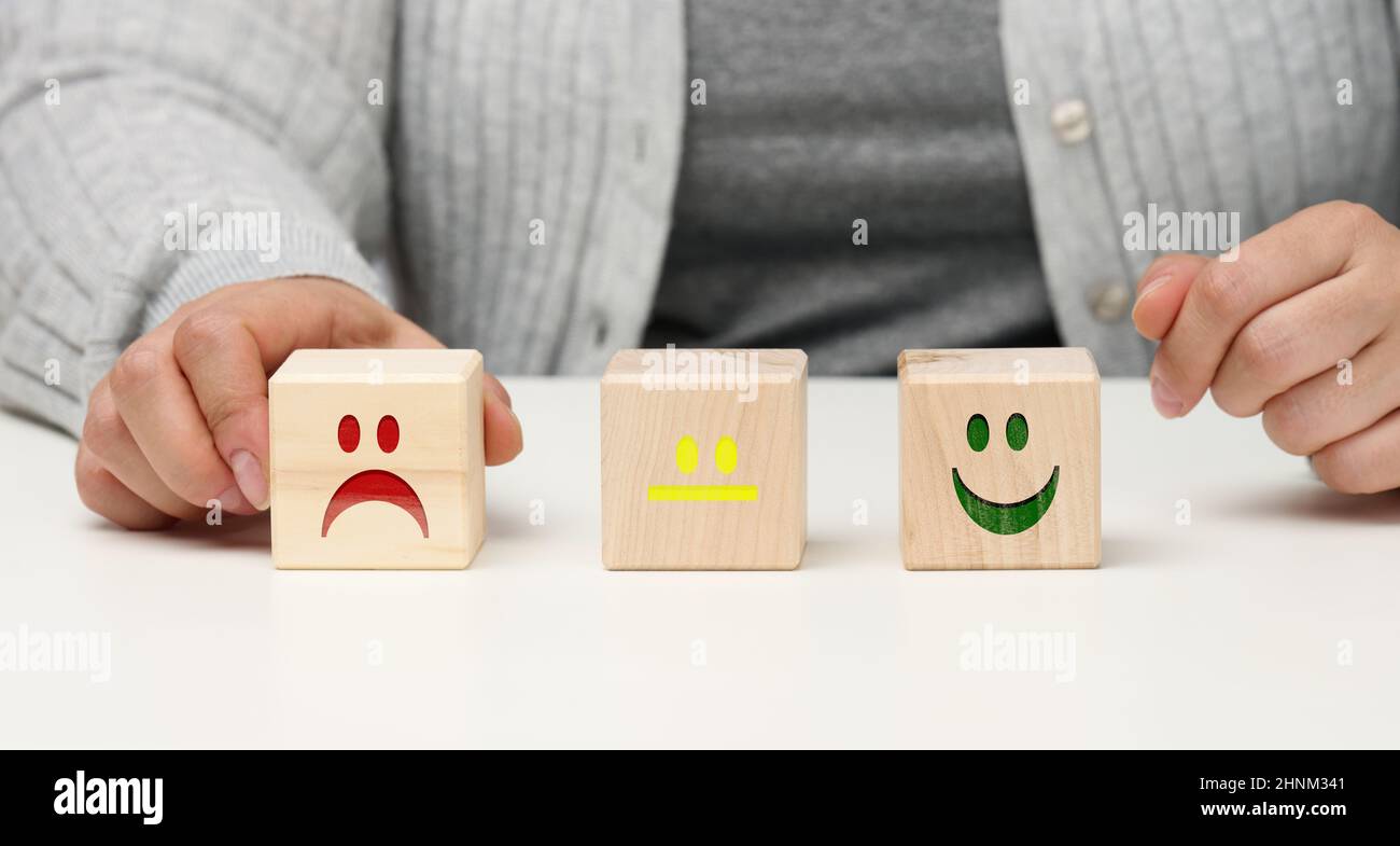 wooden blocks with different emotions from smile to sadness and a woman ...