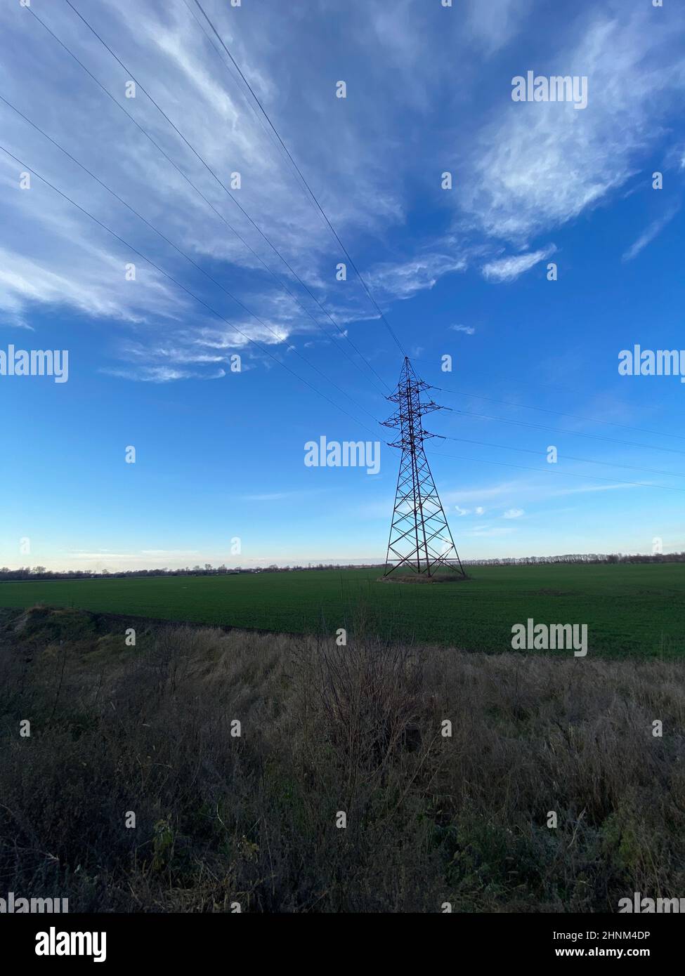 Vertical shot of transmission lines and tower in the field on a ...