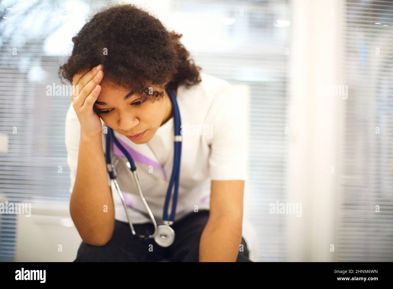 Sad depressed young african american nurse sitting with frustrated face ...