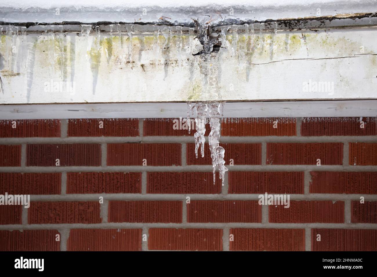 Large icicles hanging from a red brick house Stock Photo - Alamy