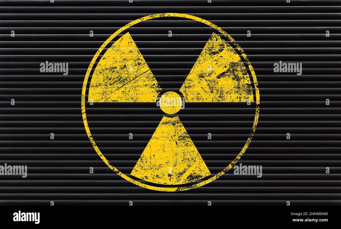 Yellow radioactive hazard warning sign painted over grunge black metal ...