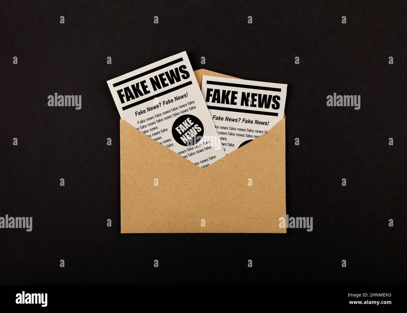 Close up brown paper mail envelope with FAKE NEWS newspapers over black ...