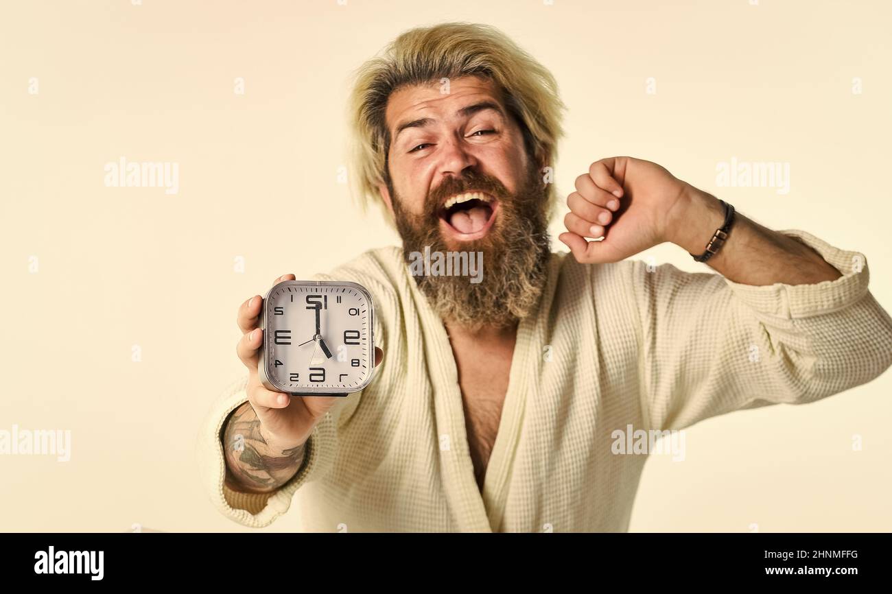 happy handsome angry man lies in bed indoors wake up turn off the alarm ...