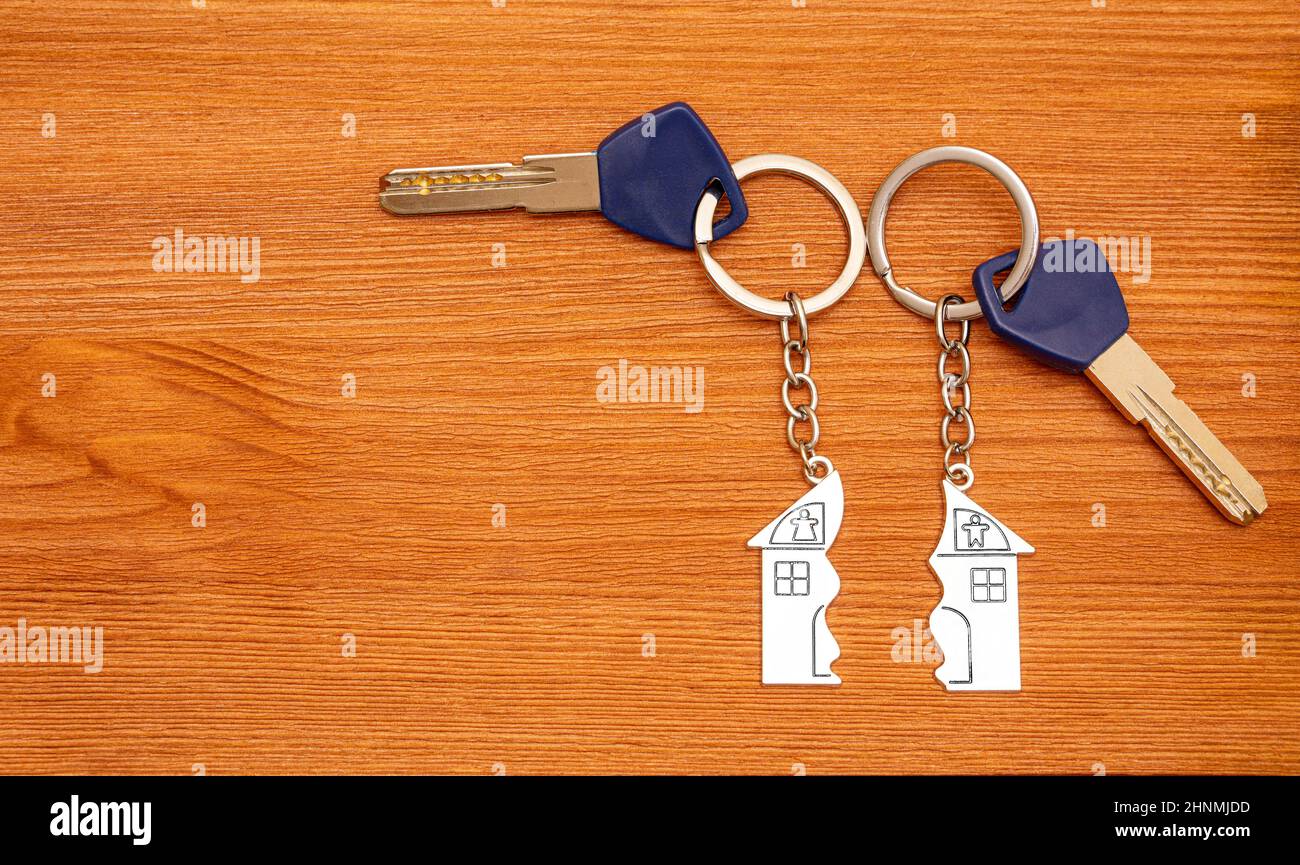 Two keys with split house matching keychains on a wooden table ...