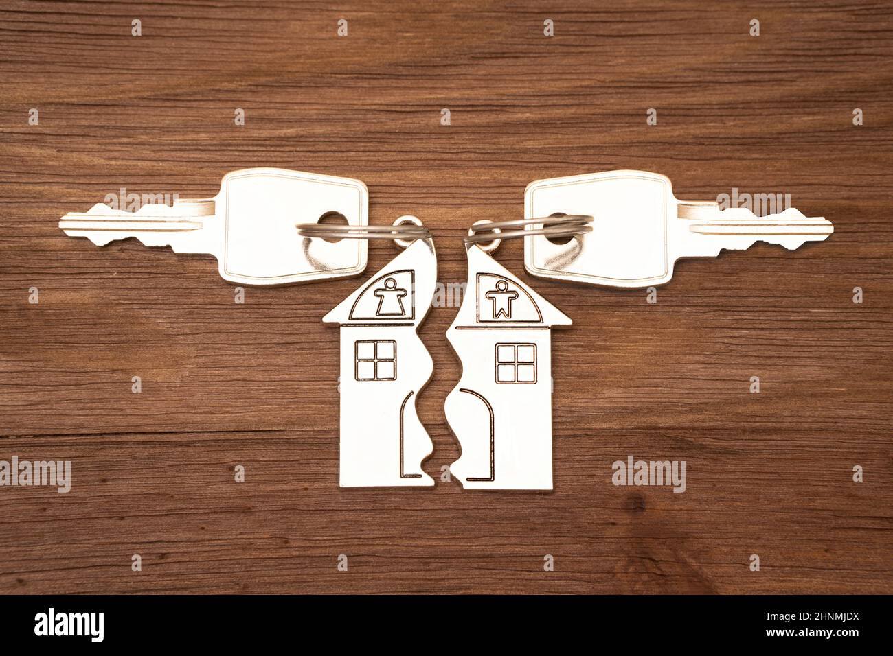 Split house matching keychains with keys on a wooden background. Moving ...