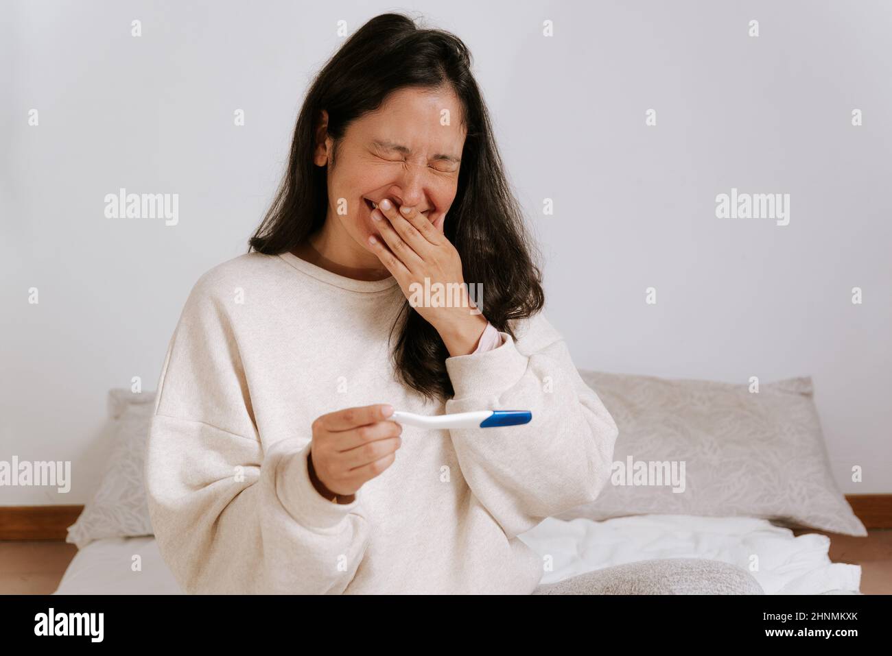 young adult woman looking at pregnancy test crying in her bedroom ...