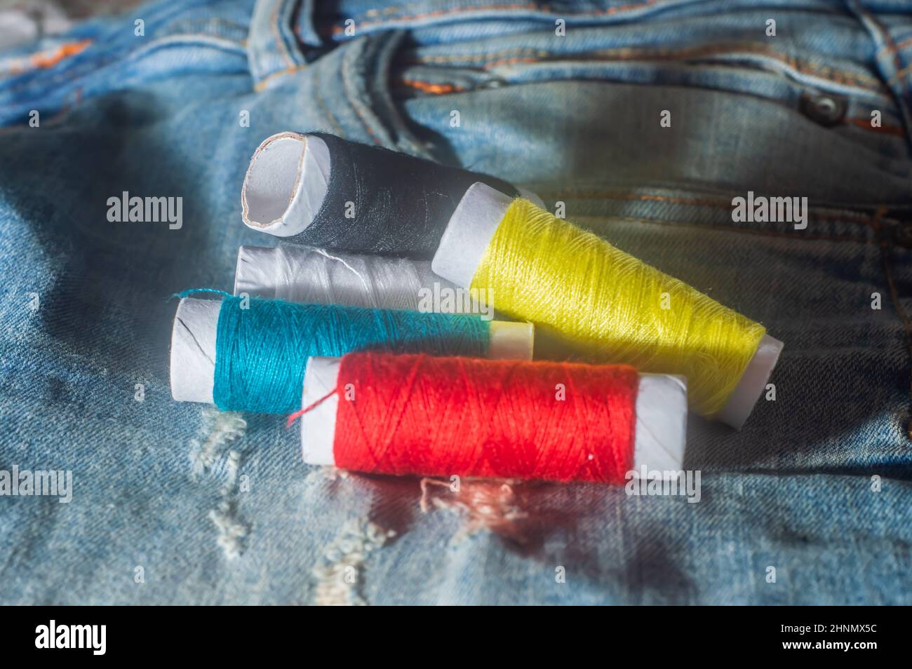 Reels with colorful sewing threads with jeans in the background, sewing ...