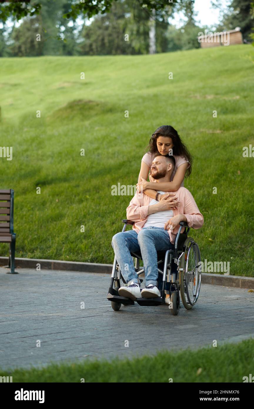 Love couple with wheelchair walking in autumn park. Paralyzed people ...