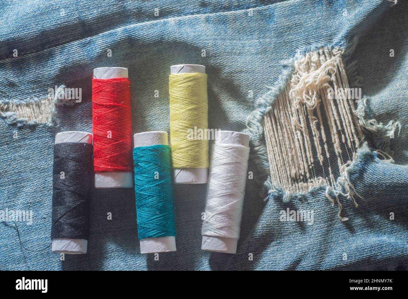 Reels with colorful sewing threads with jeans in the background, sewing ...