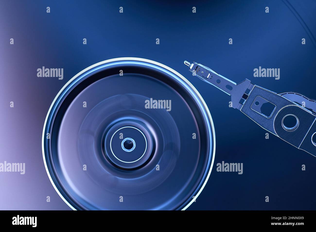 Spinning hard drive disks and writing head macro photo illuminated from ...