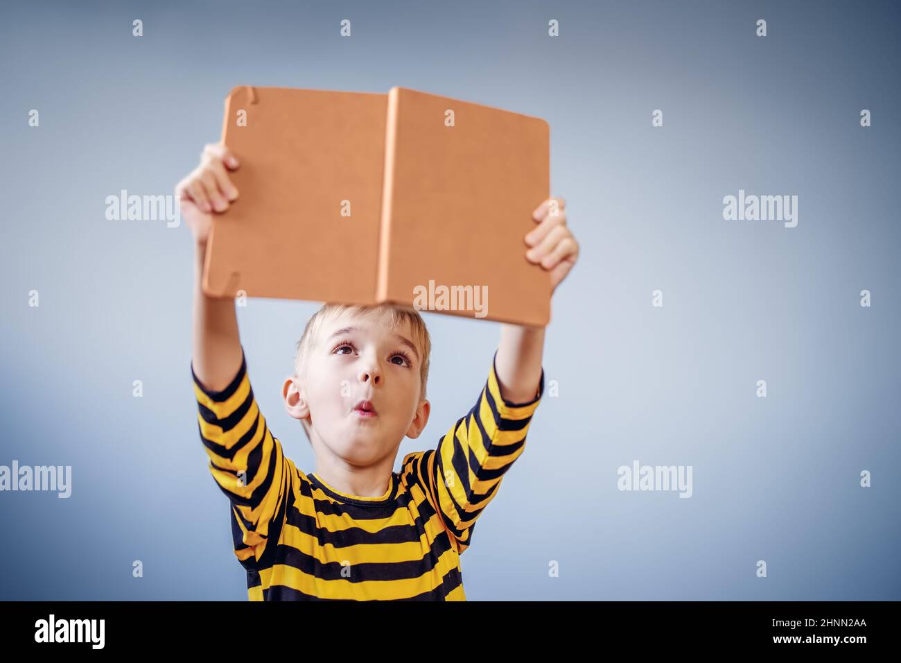 Surprised boy holding in his hands an interesting book. Concept of ...