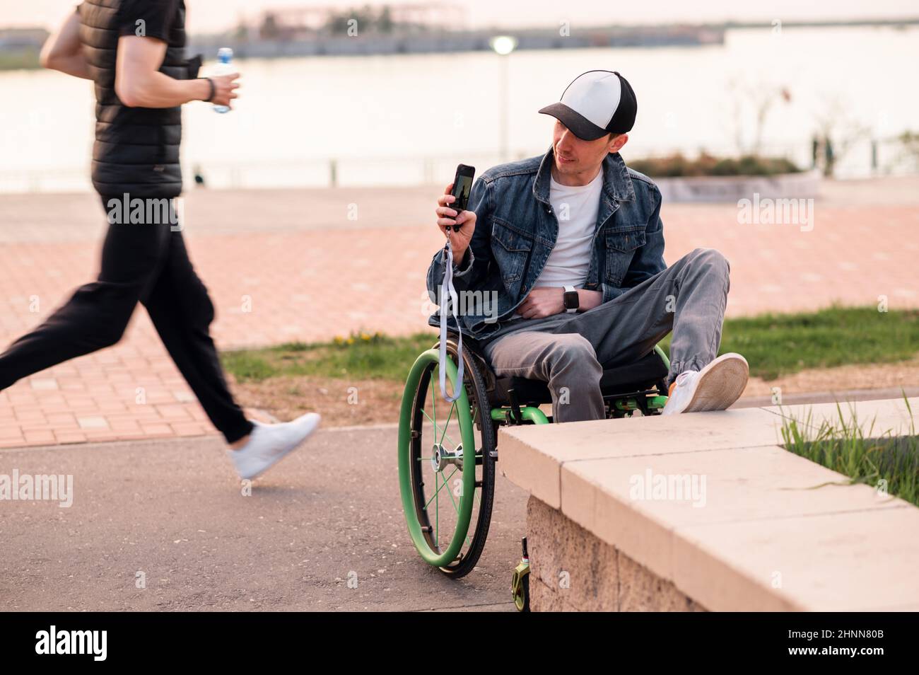a young man in a disabled person is sitting on a bench next to a ...