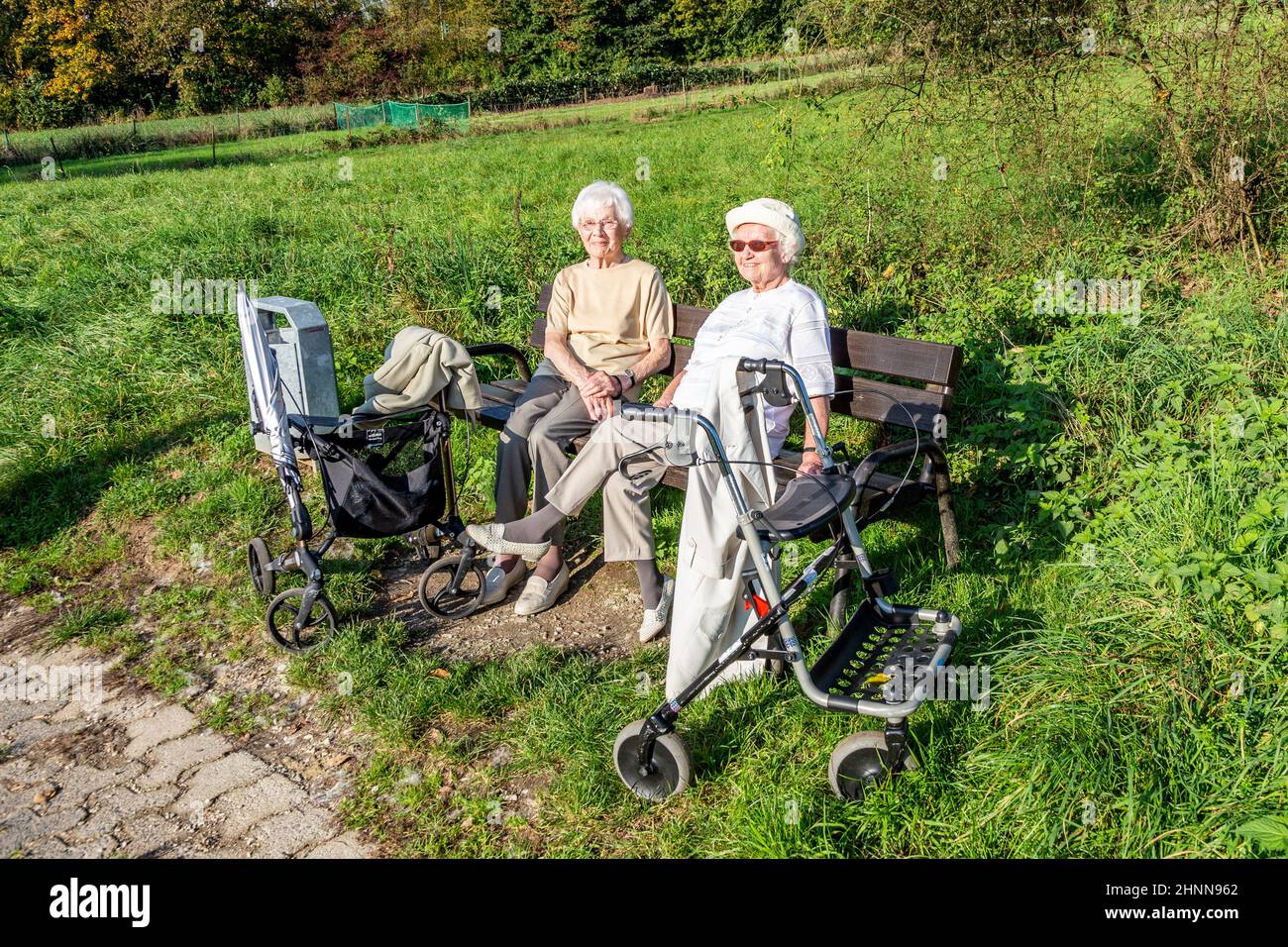 elderly female couple enjoys the spring sun while sitting on a bench ...