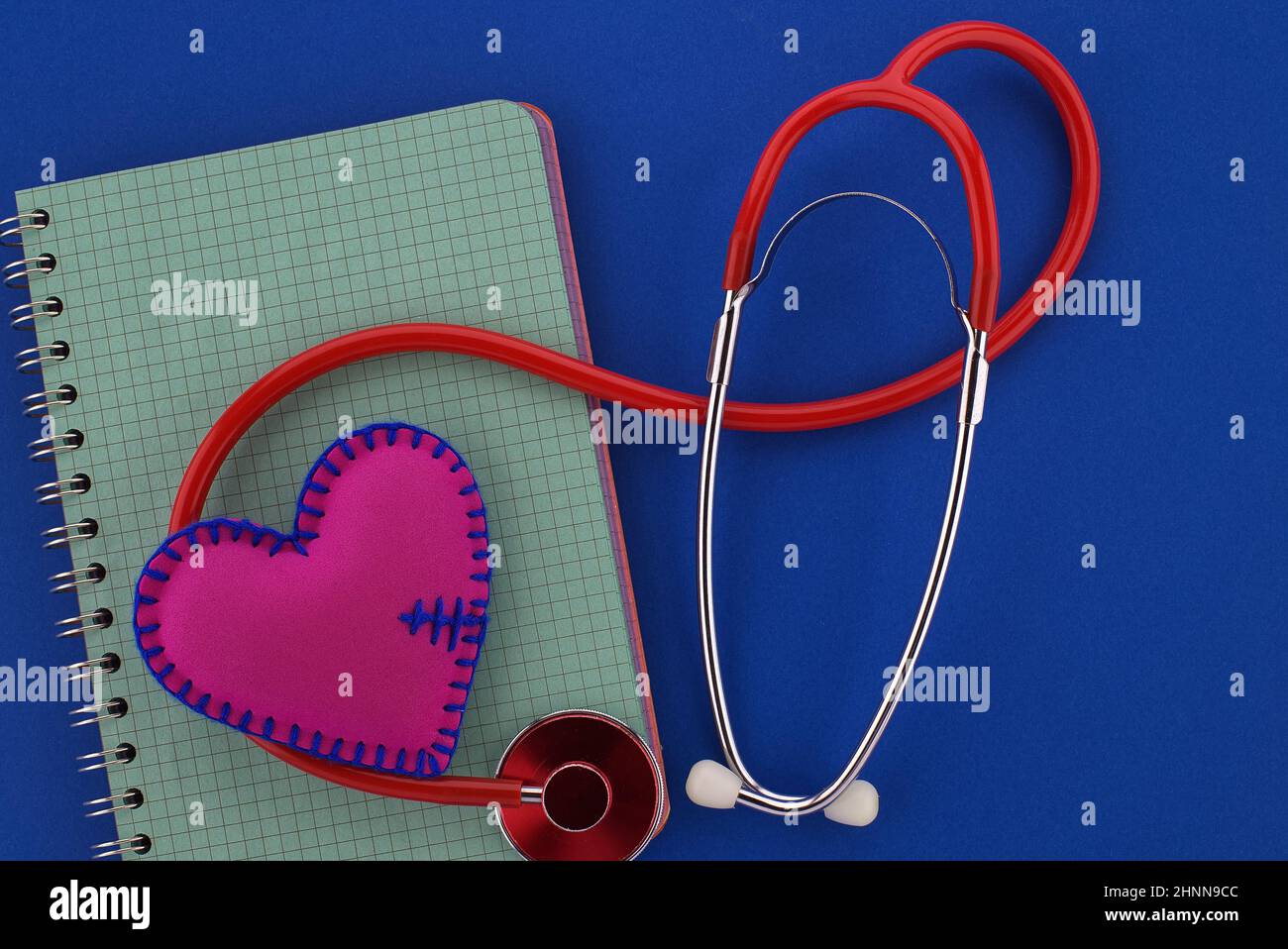 Medical concept with stethoscope and red heart and open wire bound ...