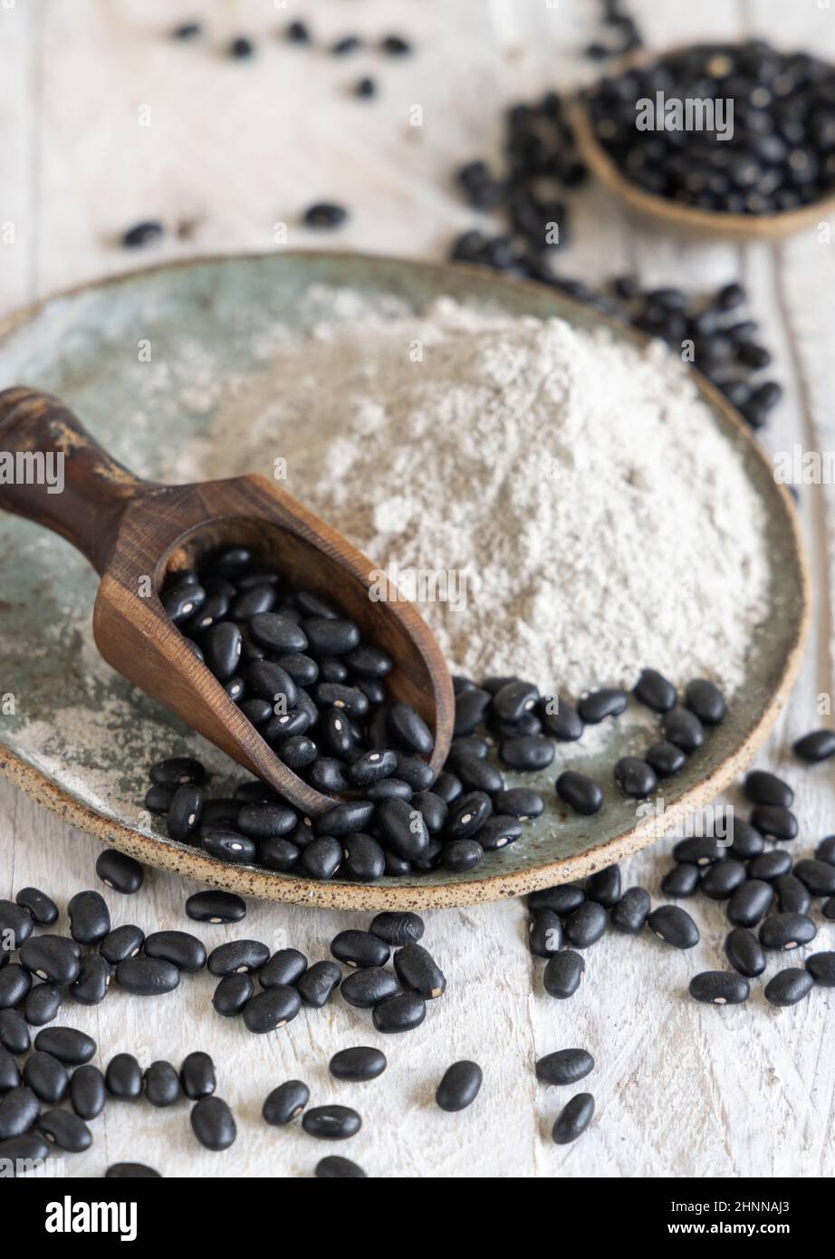 Ceramic plate with black beans flour and dried beans with a wooden ...