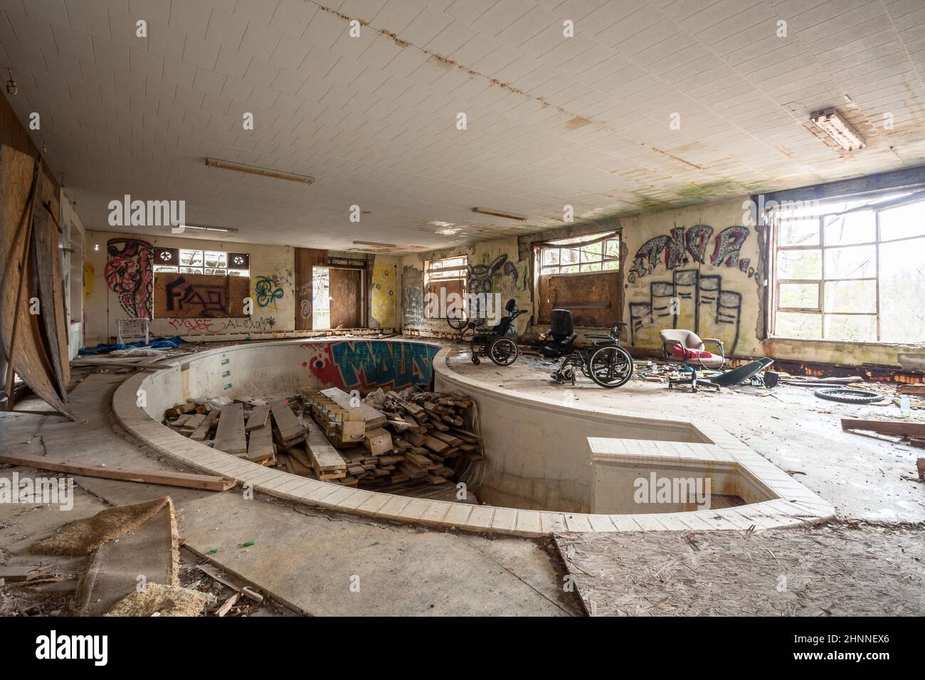 An old and abandoned indoor swimming pool with graffiti and garbage ...
